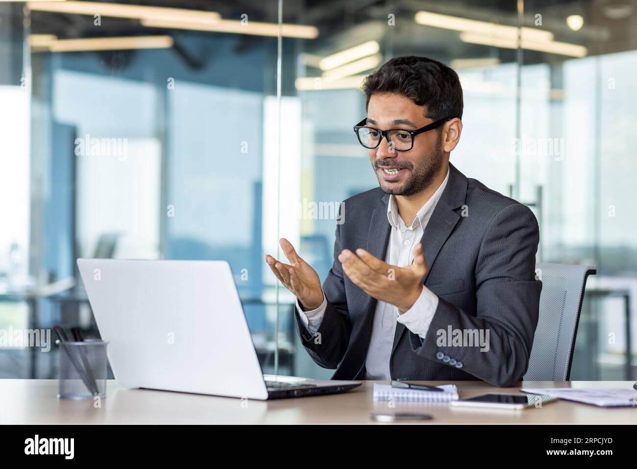 Young successful hispanic businessman talking on video call using ...