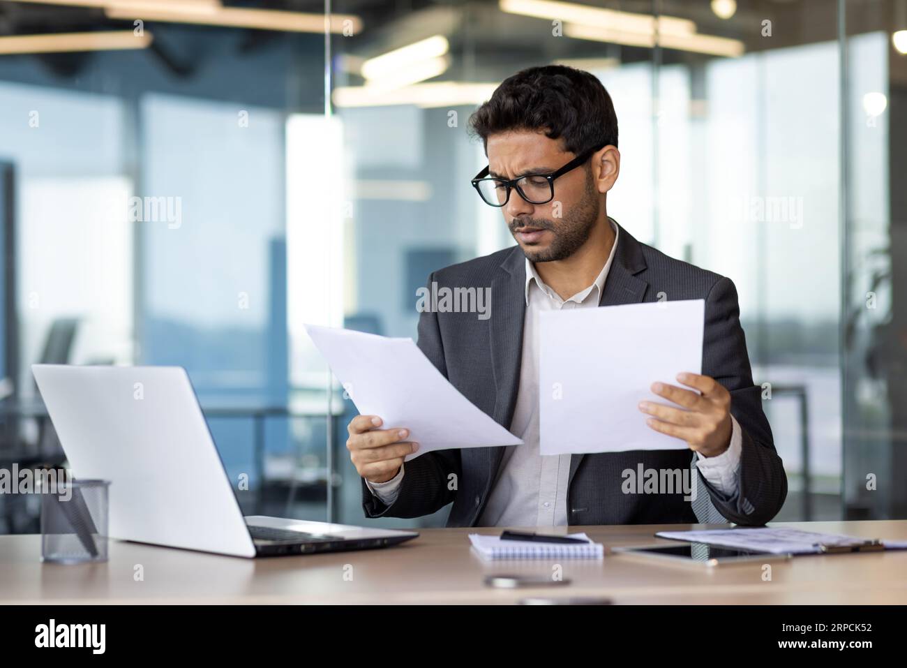Serious concentrated businessman inside office behind paper work ...