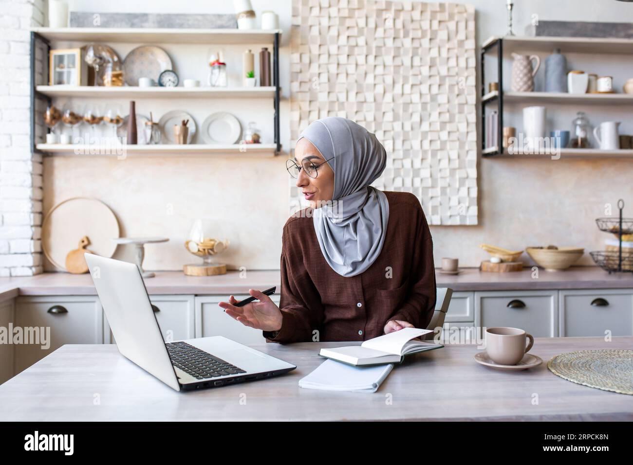 Young Muslim female teacher in hijab working from home, doing distance ...