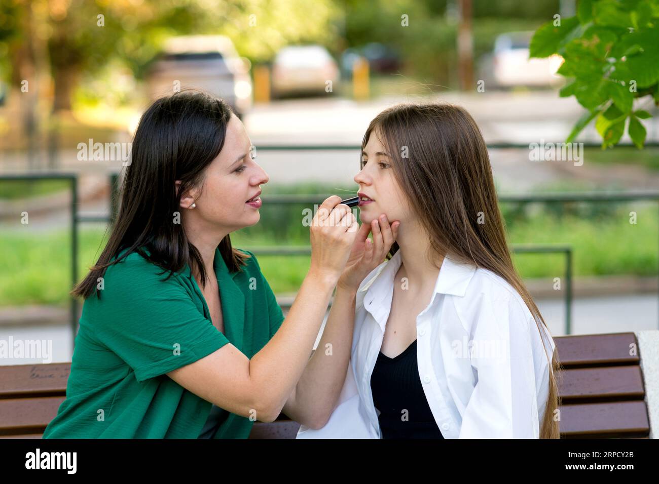Mom helps teen girl to do makeup. Mother applies lipstick to teenage ...