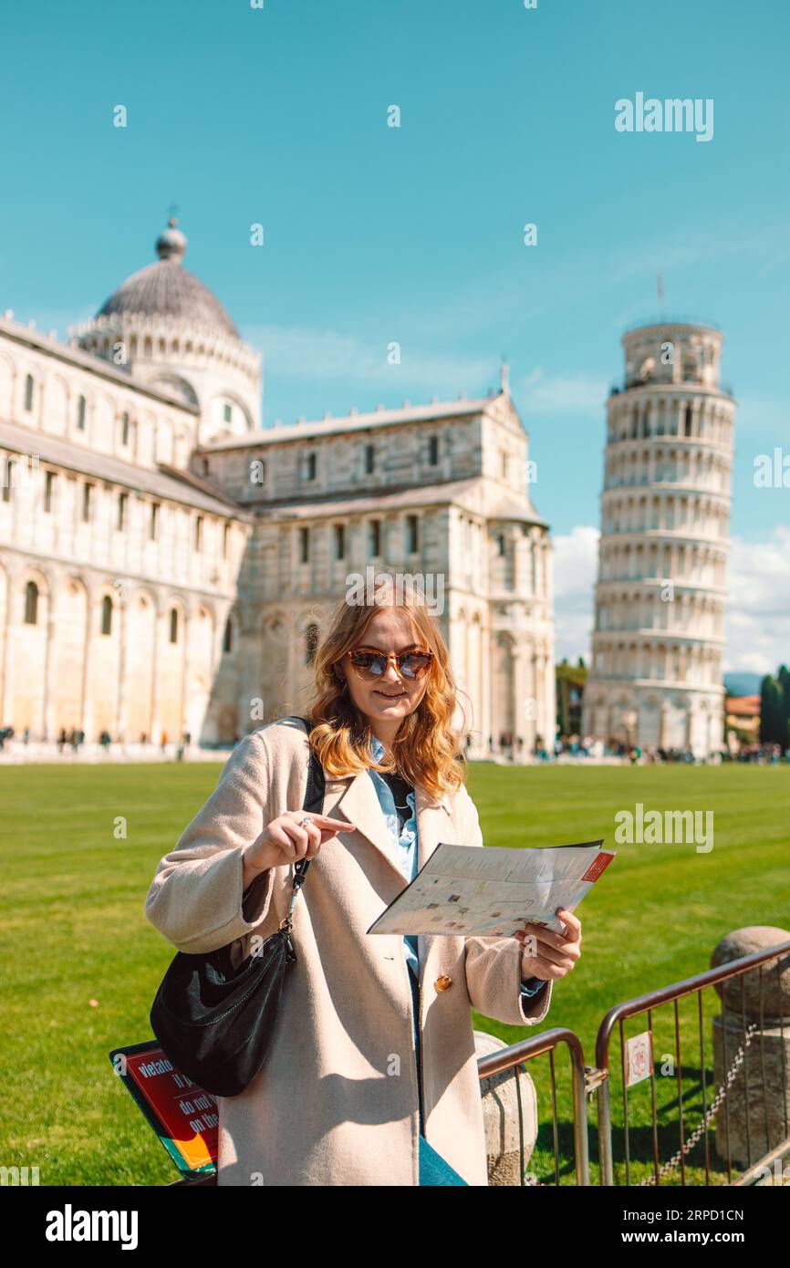 Portrait of smiling young woman with map in front in front of leaning ...