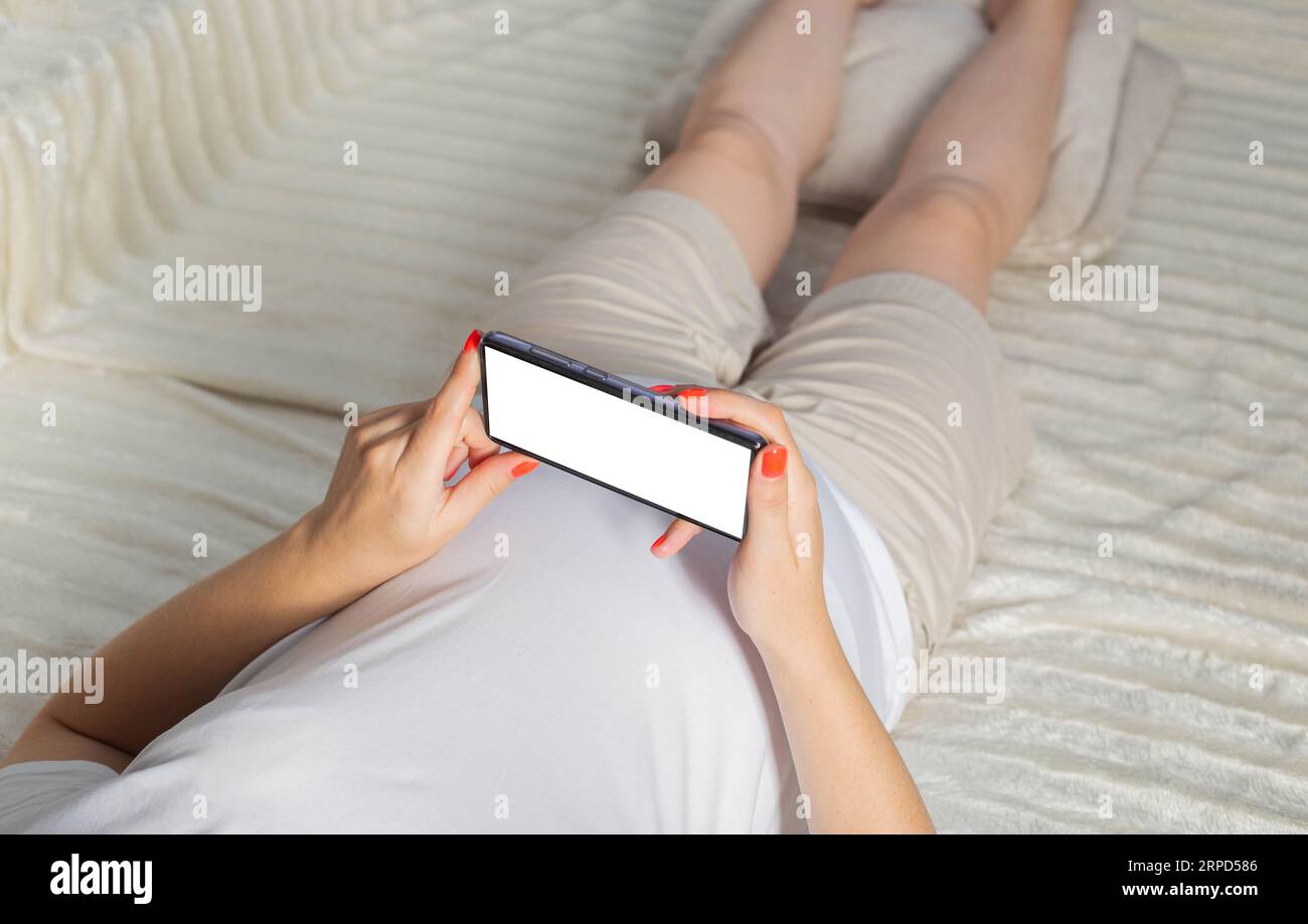 A pregnant girl with a phone in her hand against the background of a ...