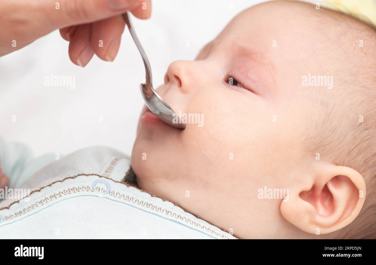A mother from a spoon gives soothing drops to a child for a good sleep ...