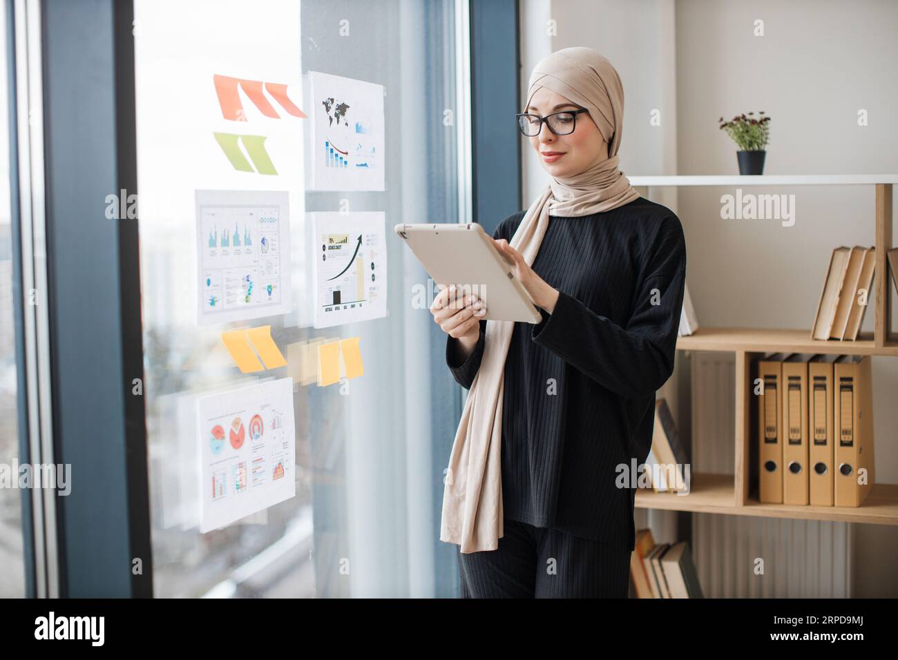 Manager with tablet standing near window with infographics Stock Photo ...