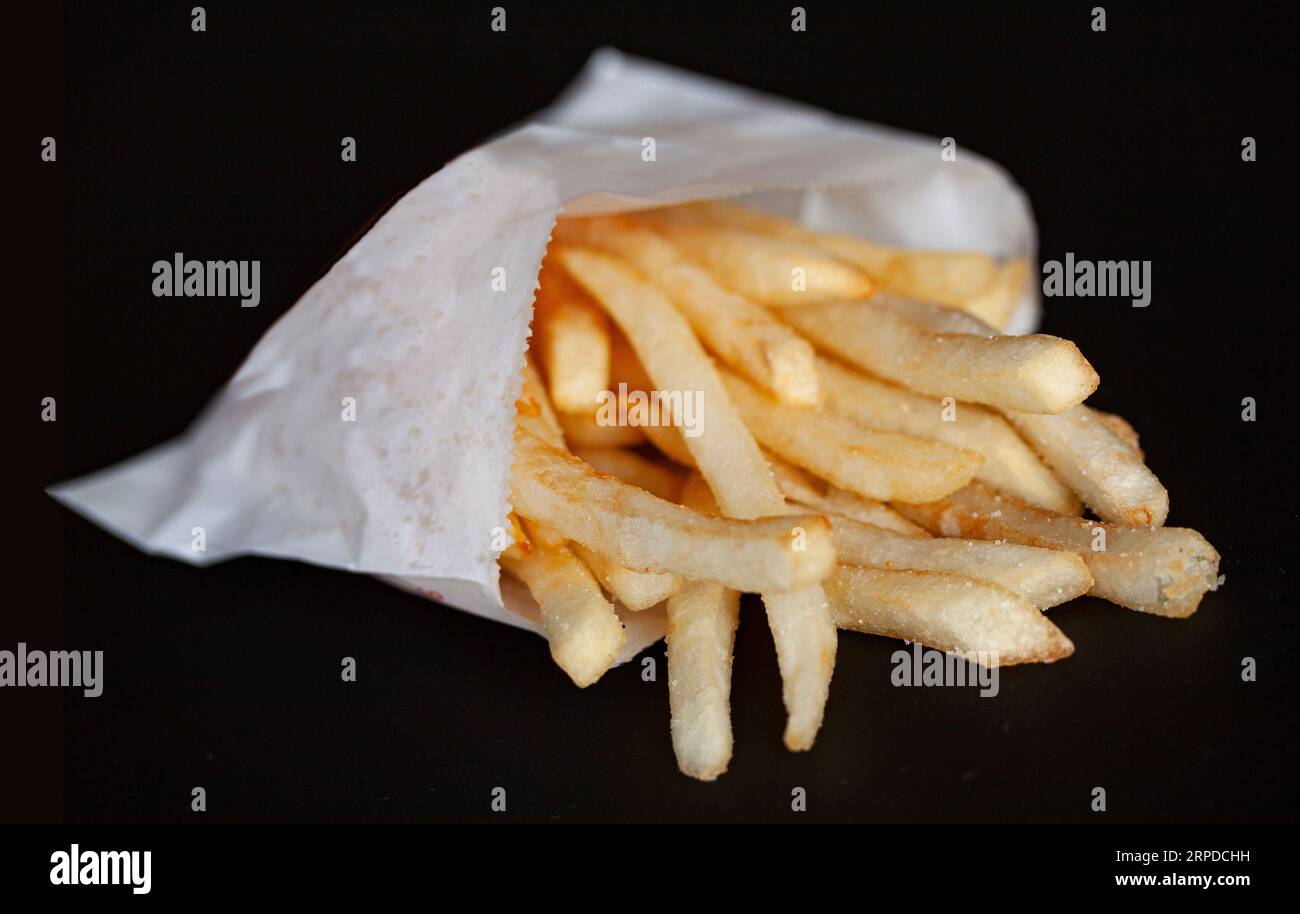 Fresh pommes frites potatoes fries in a little white paper bag isolated ...