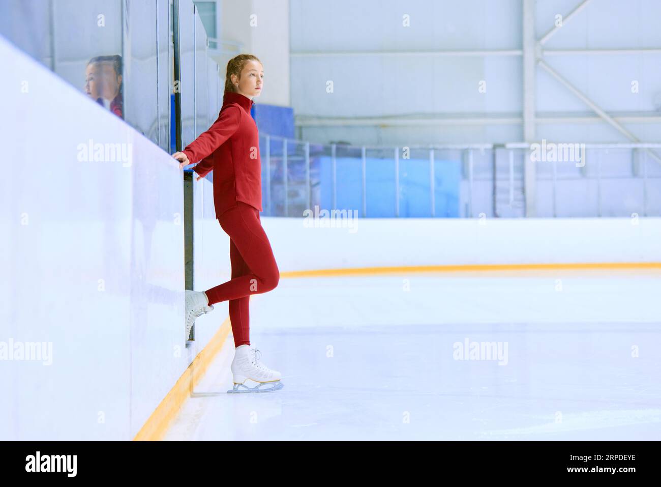Girl in red sportswear, figure skating athlete standing on ice rink ...