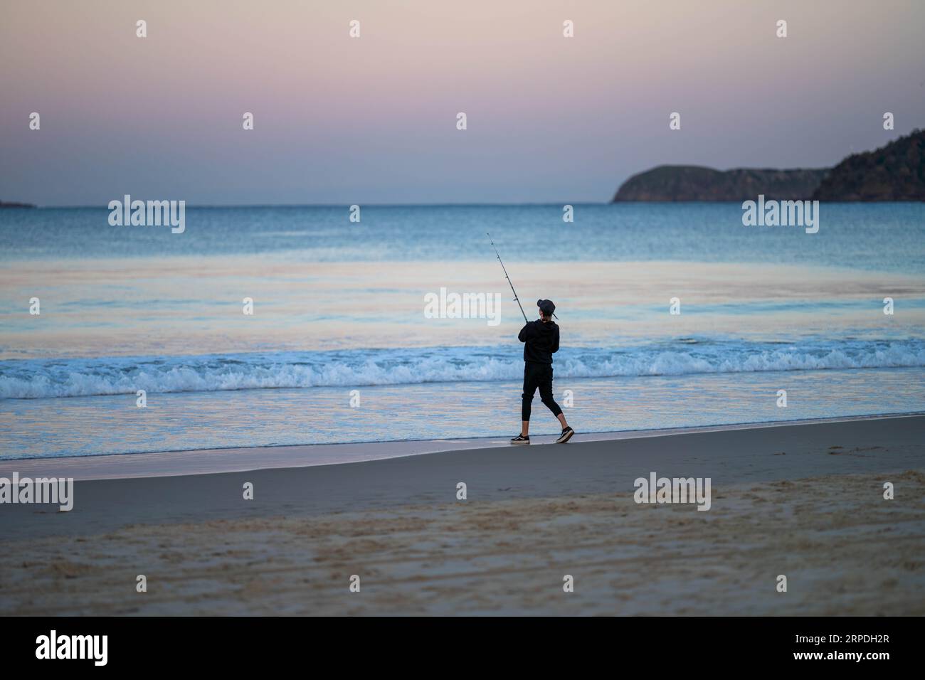 beach fishing in the ocean waves at dusk on a holiday in summer Stock ...