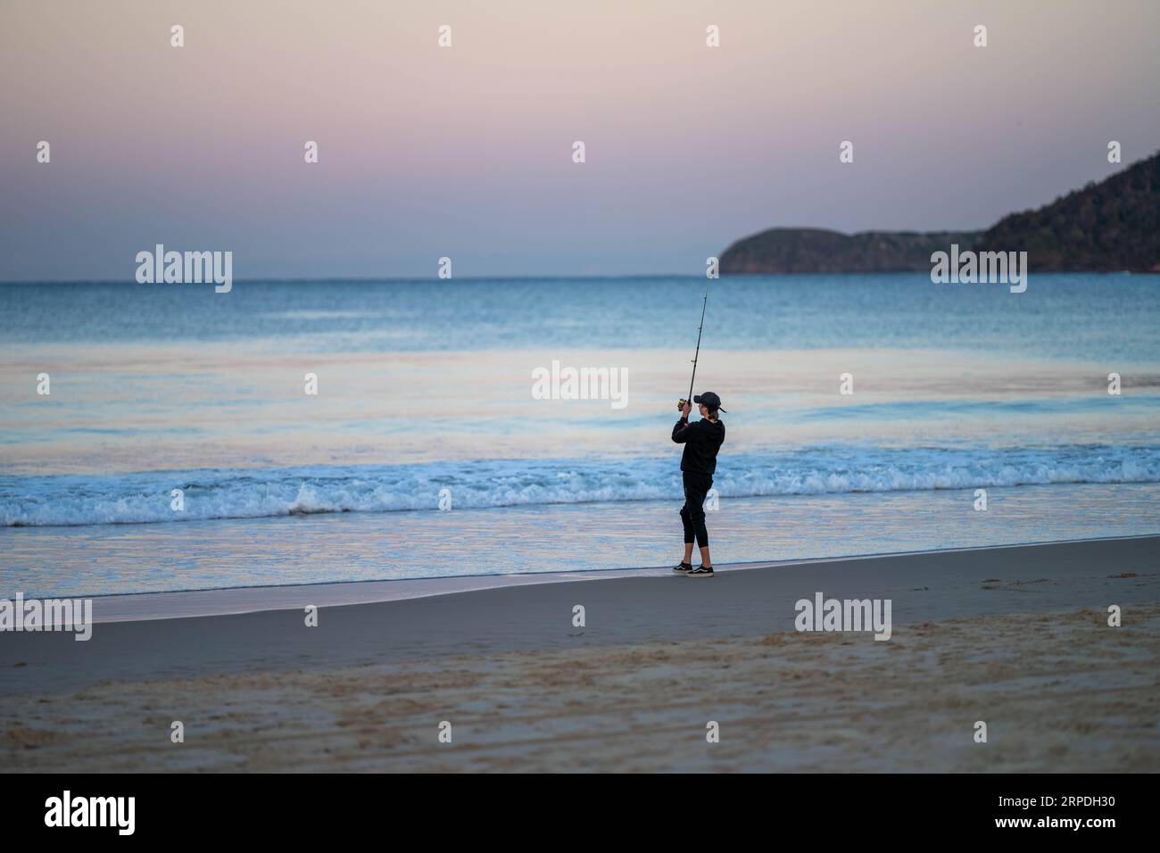beach fishing in the ocean waves at dusk on a holiday in summer Stock ...