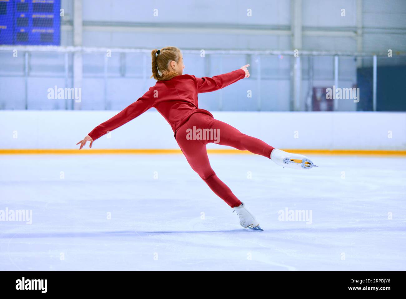 Teen girl in red sportswear, figure skater in motion skating on ice ...
