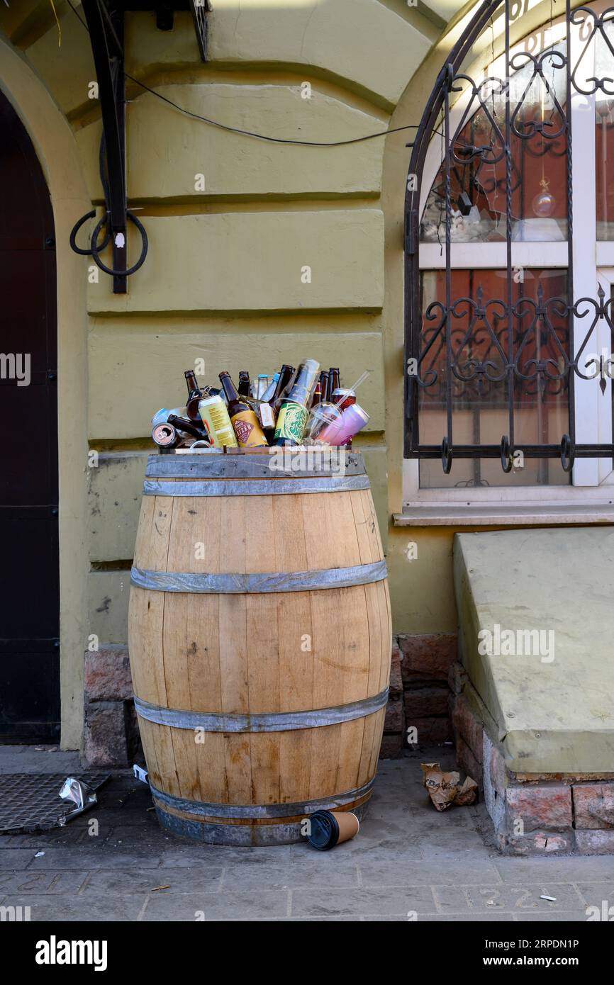 A wooden barrel full of empty bottles near the bar in the early morning ...