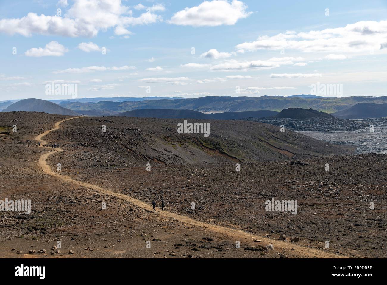 Panoramic view over lava field with hikers on path near mountain ...