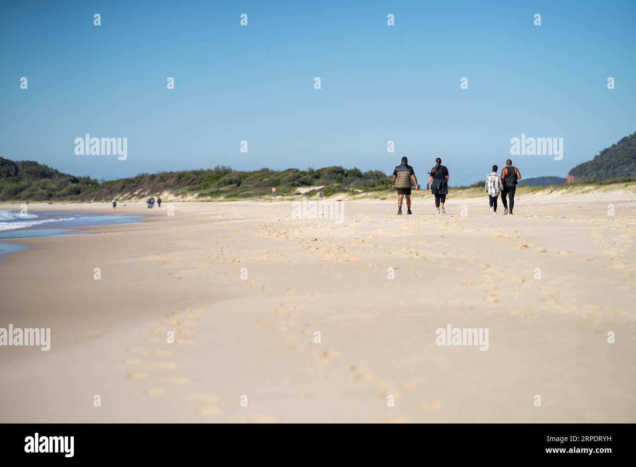 walking on Sandy beach, next to the sea with waves breaking behind, and ...