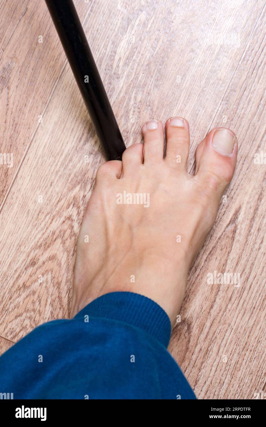 Kicking a toe on a chair leg close up Stock Photo - Alamy
