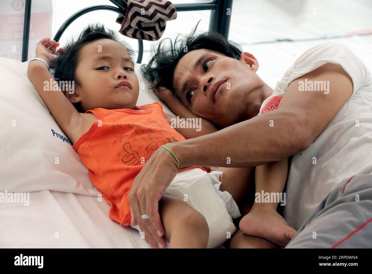 (190813) -- CAVITE PROVINCE, Aug. 13, 2019 -- A father attends to his sick child as they rest ...