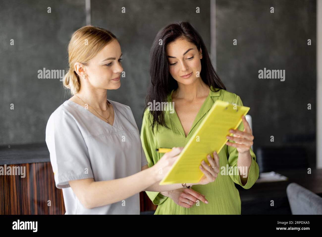 Nurse talks with a woman in lobby Stock Photo - Alamy