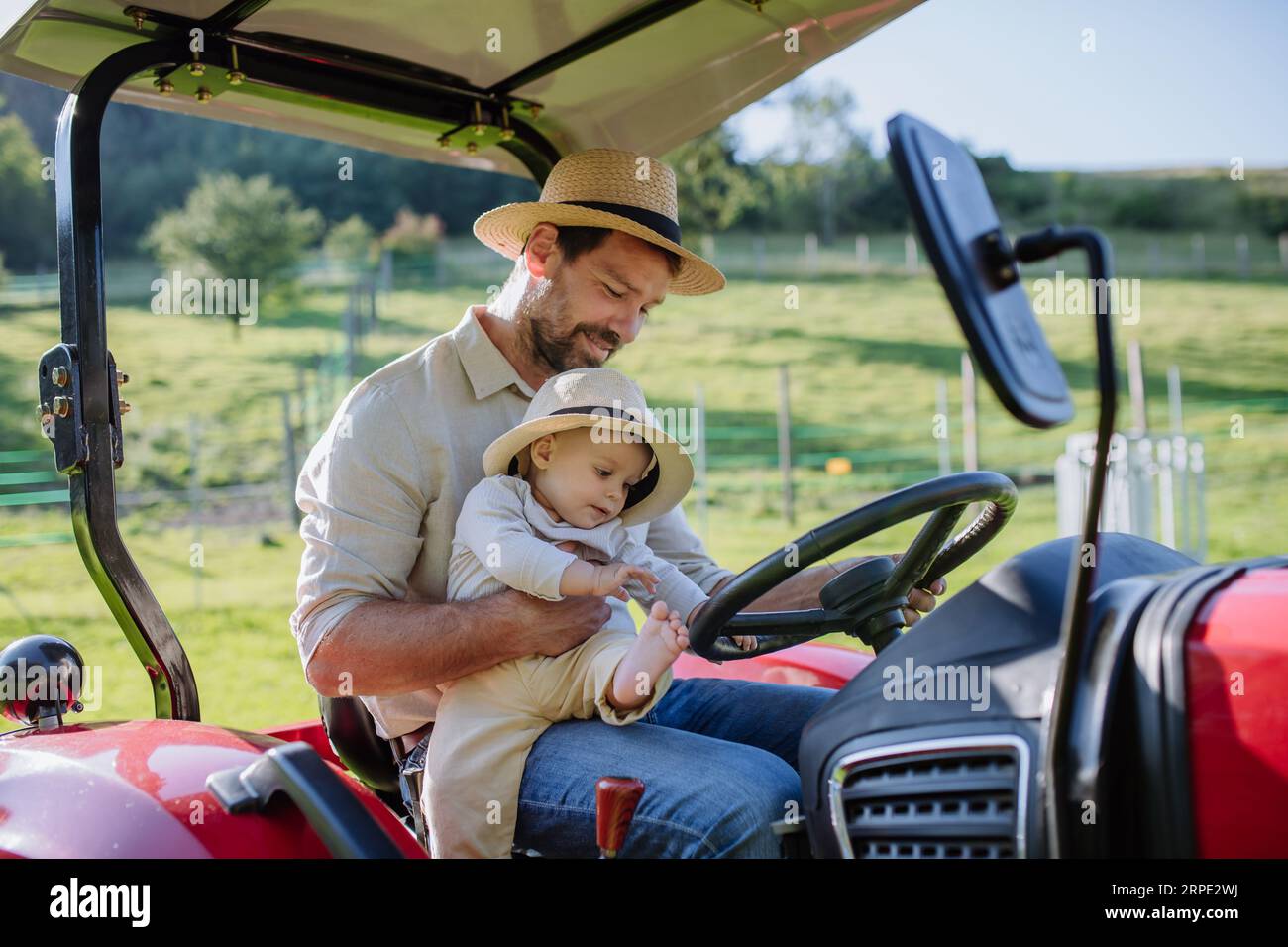 Farmer father riding tractor with his little baby son Stock Photo - Alamy