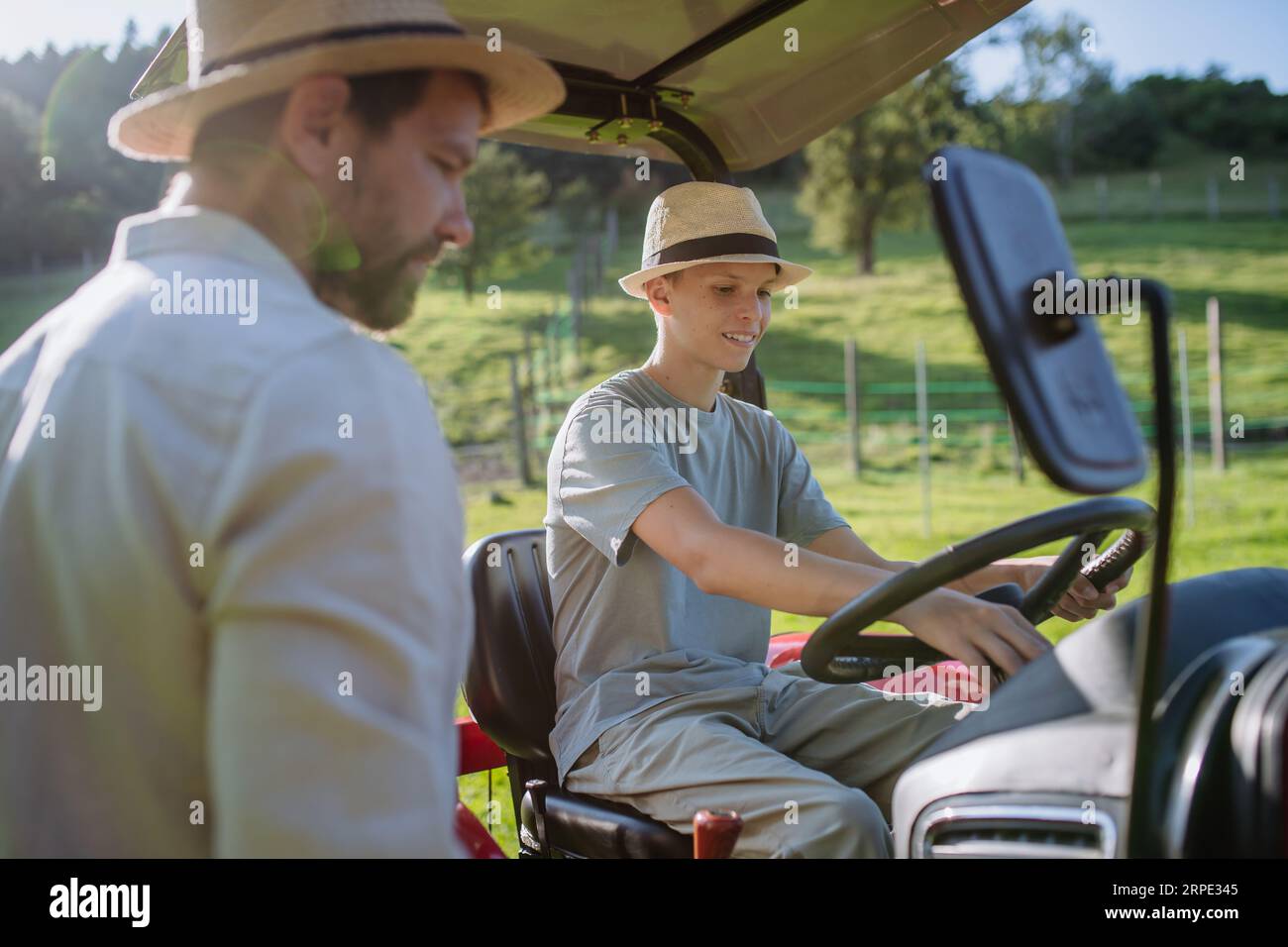 Farmer father letting his son drive the tractor Stock Photo - Alamy