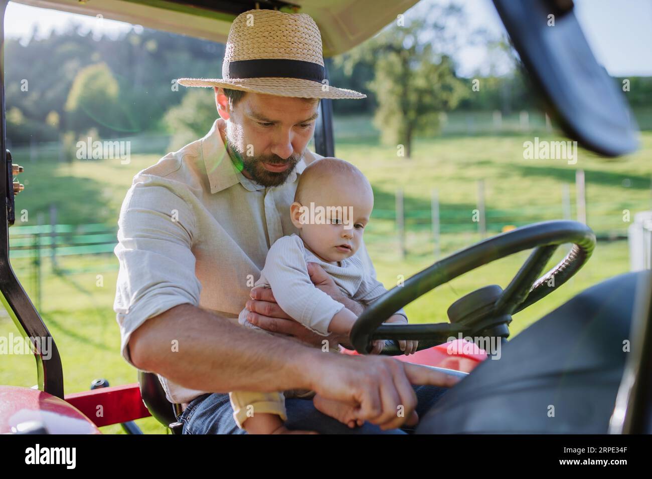 Farmer father riding tractor with his little baby son Stock Photo - Alamy