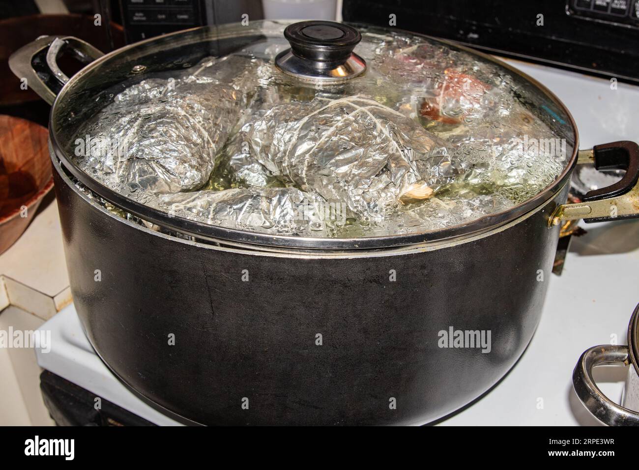Photography of pot on stove boiling tamales in silver foil Stock Photo ...