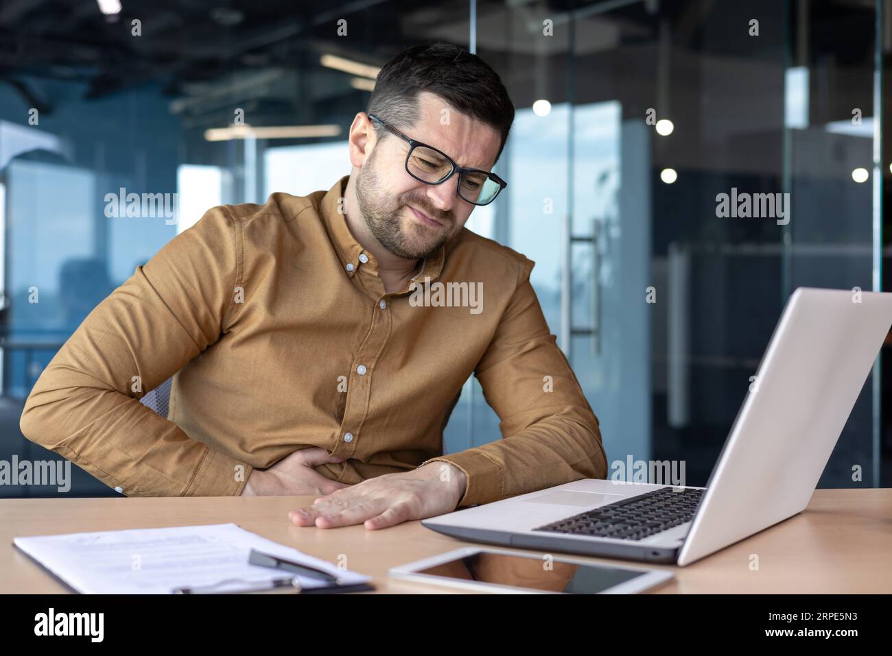 Unwell at work. Young male office worker, businessman sitting in the ...