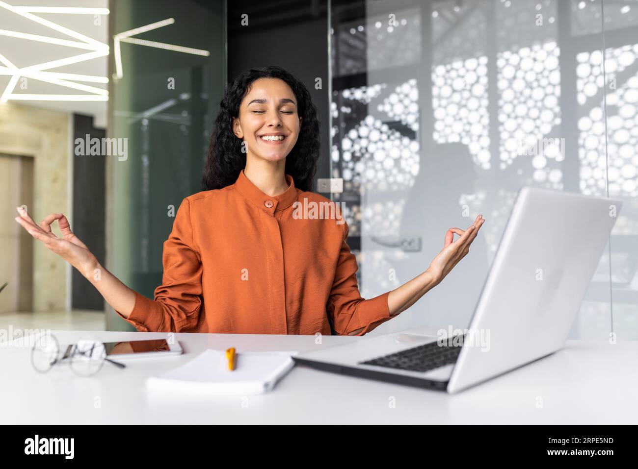 Young beautiful successful woman meditating in lotus position while ...