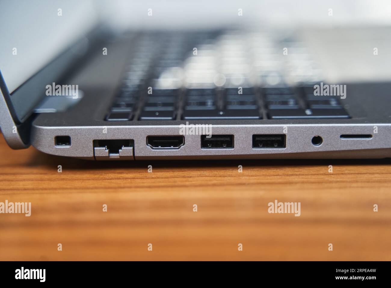 Side view of a gray laptop keyboard on a wooden table. USB ports on a ...