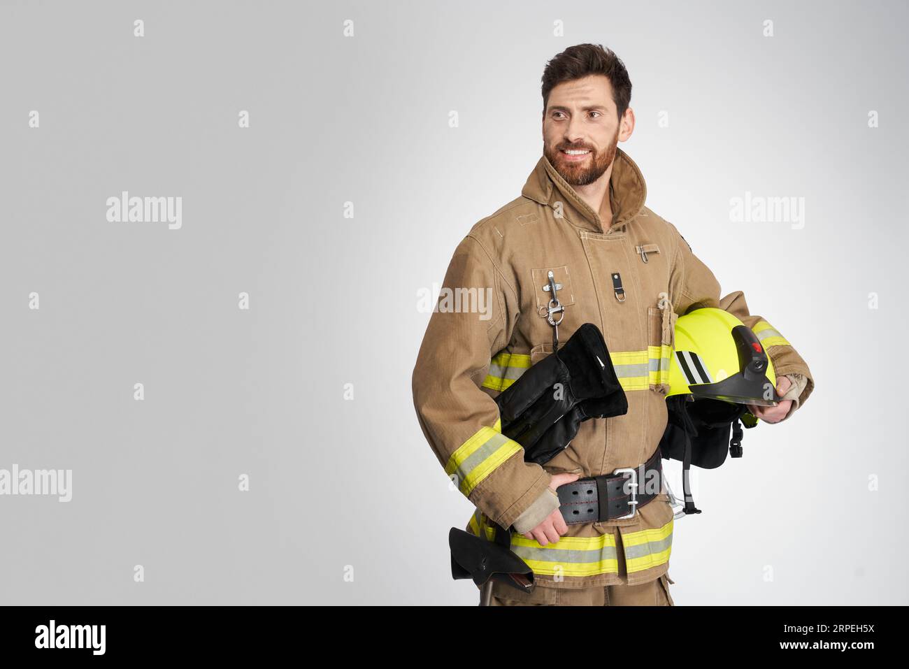 Confident guy in fireman's uniform carrying helmet, while posing in ...