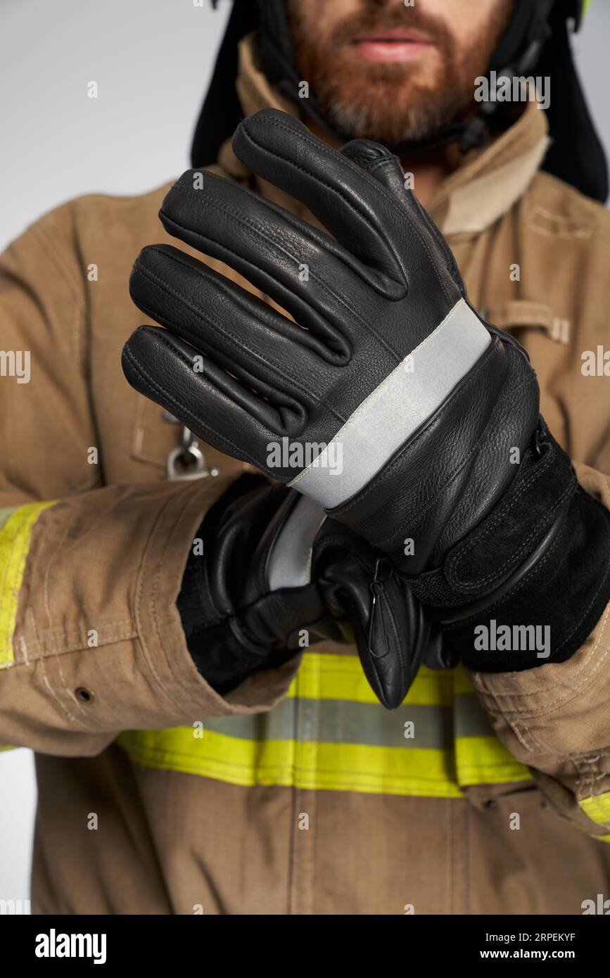 Unrecognizable bearded firefighter wearing black protective gloves ...
