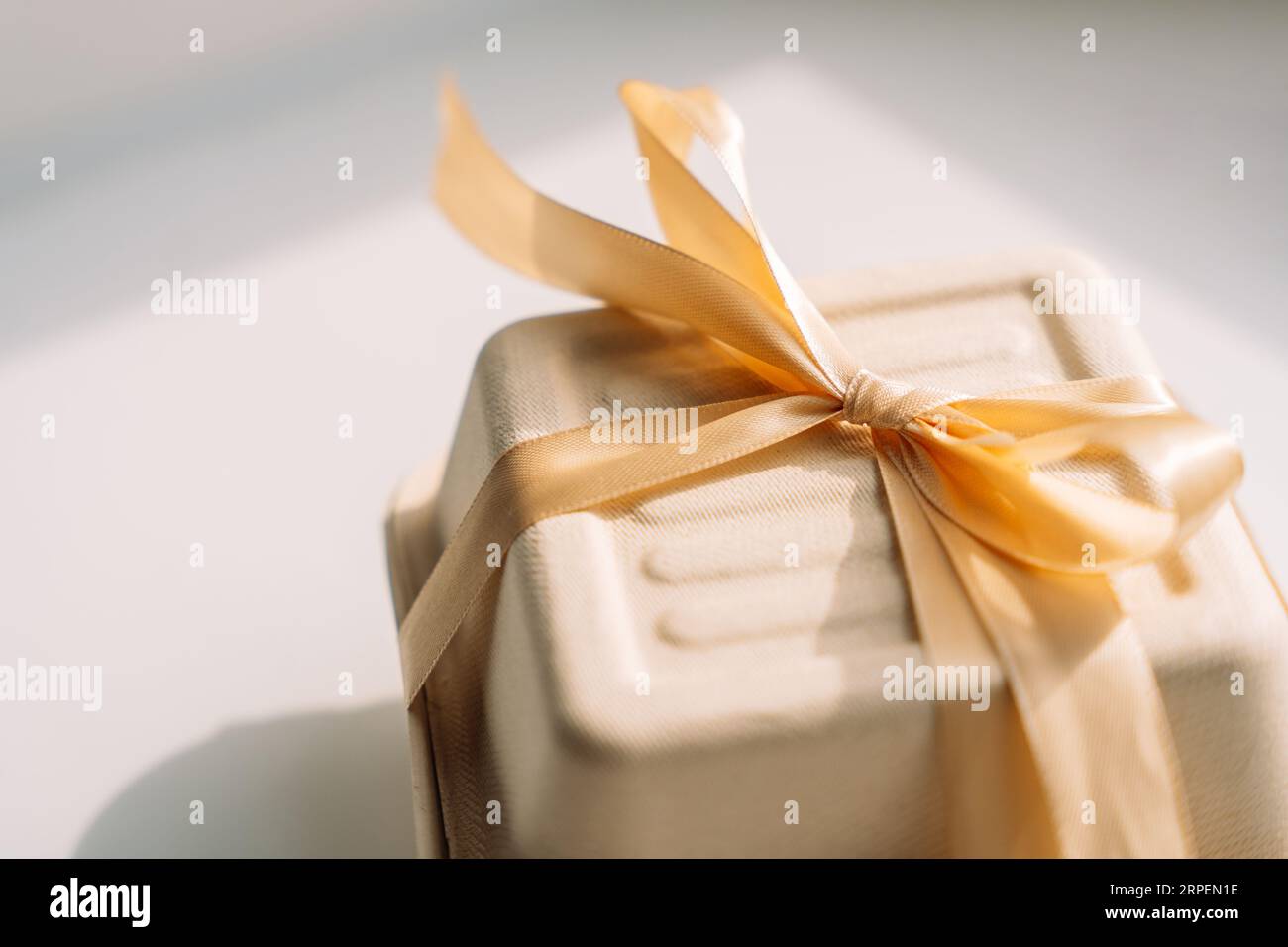 Light color gift container wrapped with ribbon on white background in ...