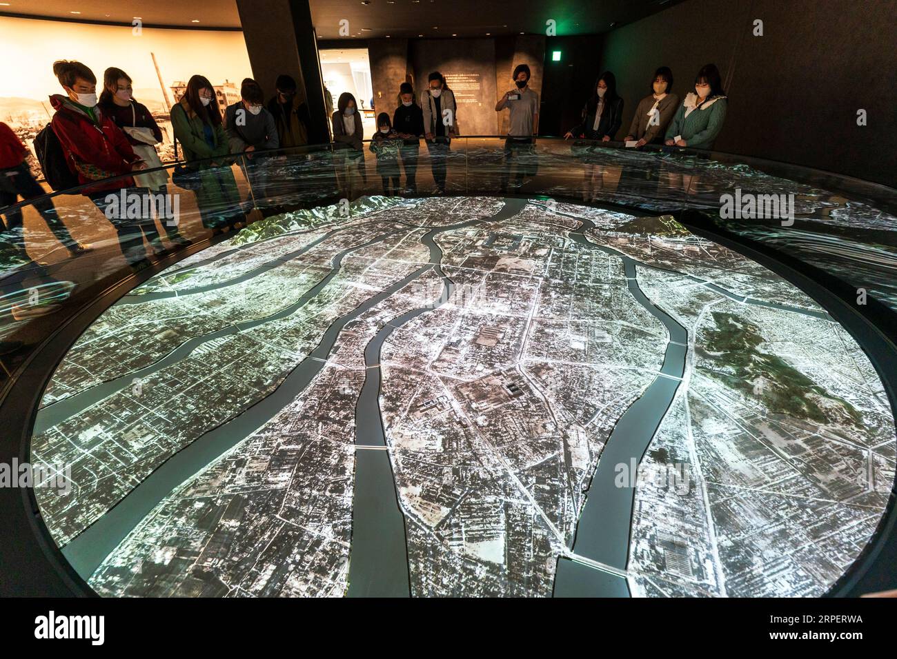 Interior of Hiroshima Peace Museum. People in darkened area viewing a ...