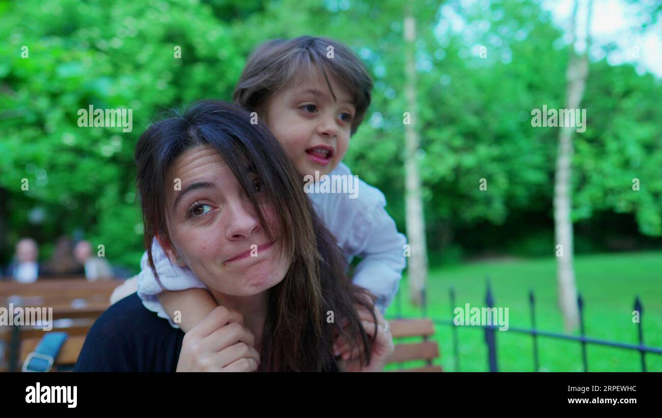 Abrasive little boy climbing on top of mother's neck harshly, showing ...