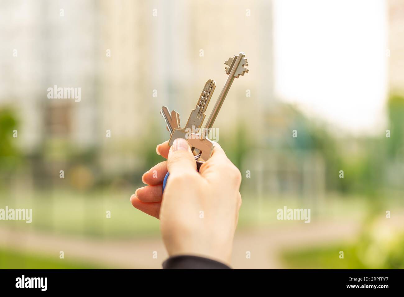 Hand holding keys in front of building Stock Photo - Alamy