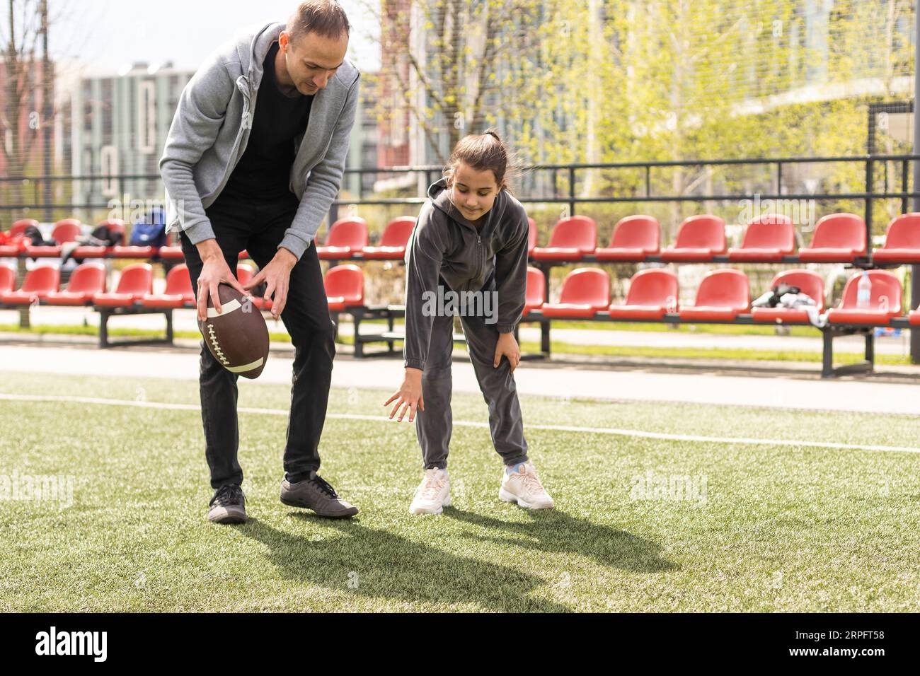 girl holding an oval brown leather rugby ball and smiling while playing ...