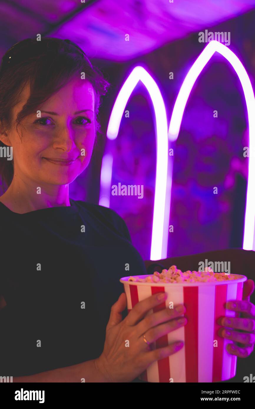 Happy girl with popcorn box in neon lights. Movie theatre popcorn ...