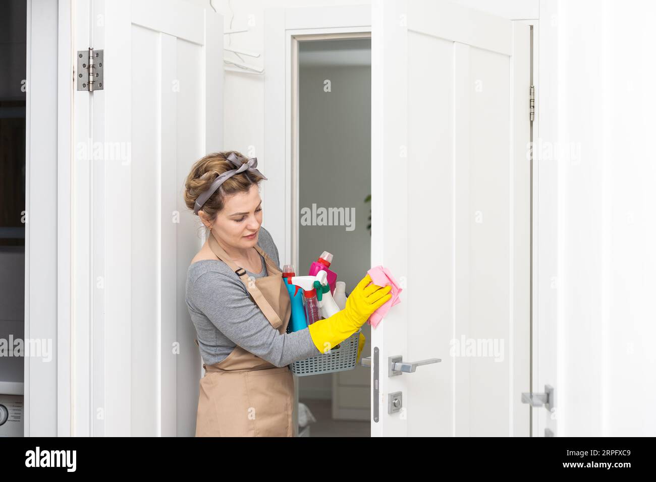 Woman cleaning and polishing the kitchen worktop with a spray detergent ...
