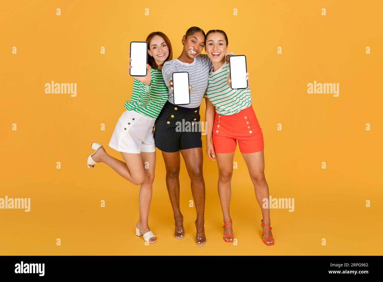 Stylish attractive young ladies showing phones with blank screen Stock ...