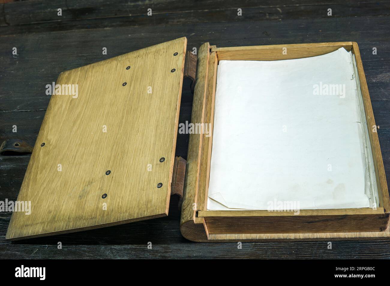 old log book in a wooden case with clasps on a black tabletop, open ...