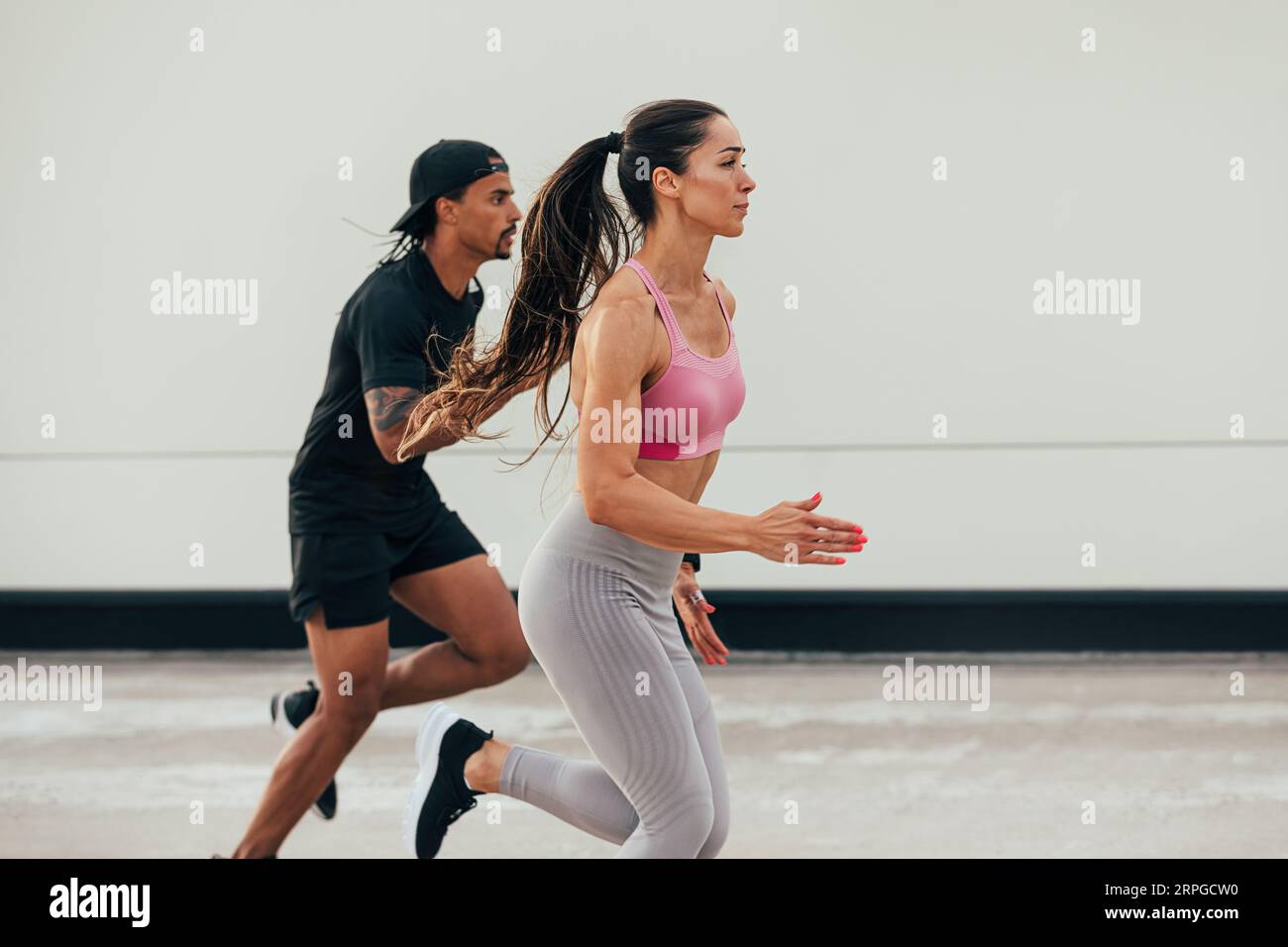 Two athletes running together outdoors. Woman and man sprinting on the ...