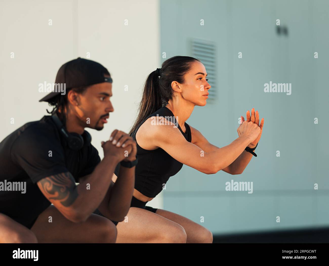 Side view of two athletes doing squats at sunset Stock Photo - Alamy