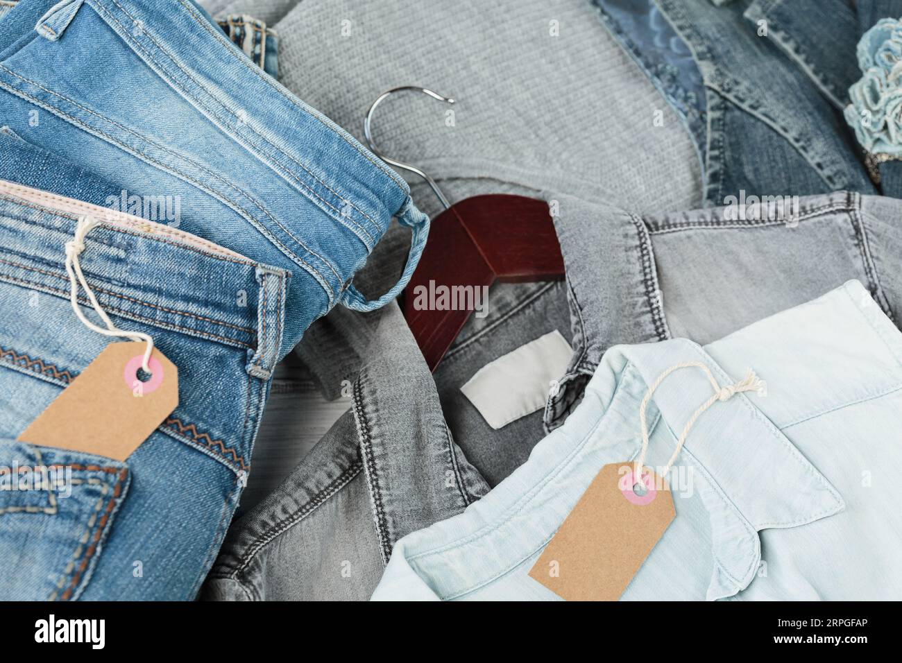 Stack of blue jeans, shirts and empty tags from craft paper Stock Photo ...