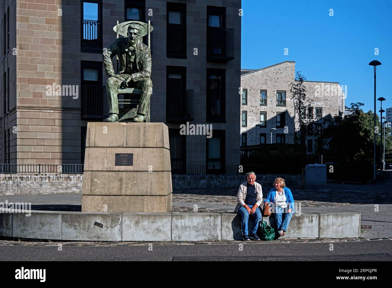 Elderly couple sitting next to the seated statue of Scottish architect ...