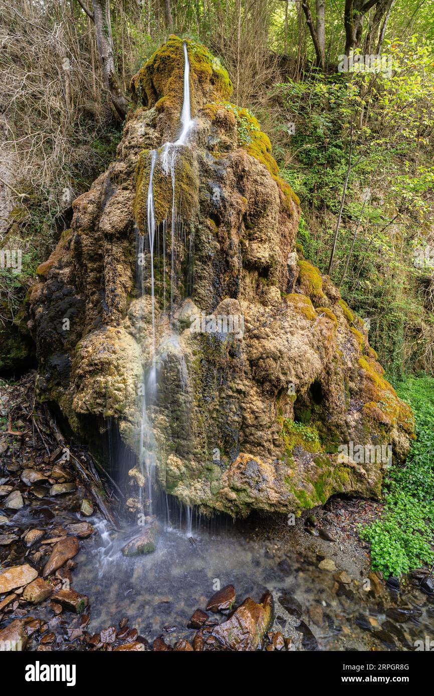 Scenic vertical view of waterfall on rock covered in limestone and moss ...