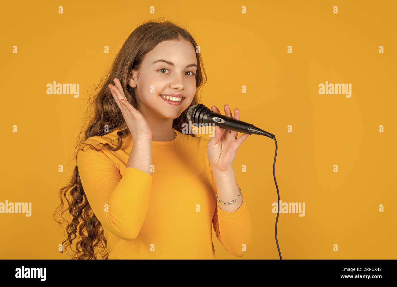 cheerful teen kid with microphone on yellow background Stock Photo - Alamy