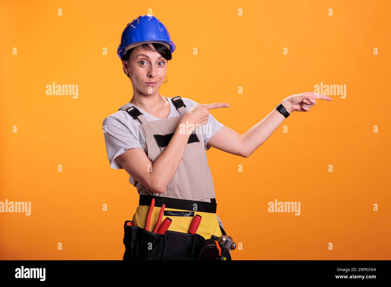 Confident handywoman pointing left or right sides, showing sideways and ...