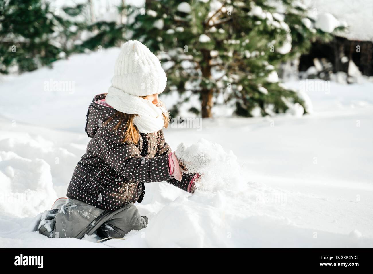 Little cute girl in white hat,scarf snood is lying,playing in snow. Kid ...