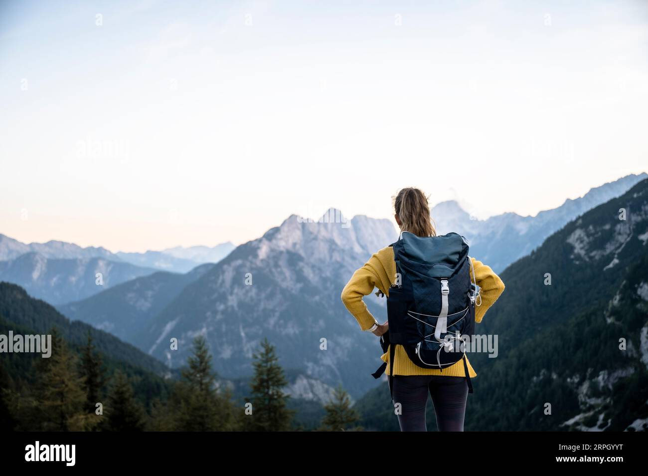 View from behind of a young female hiker with backpack on her back ...