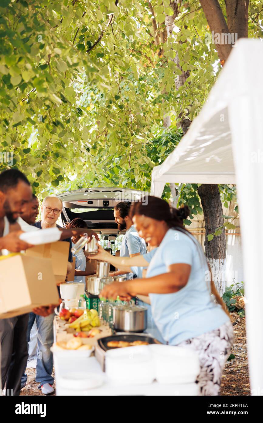 Happy african american woman and team volunteers distribute meal boxes ...