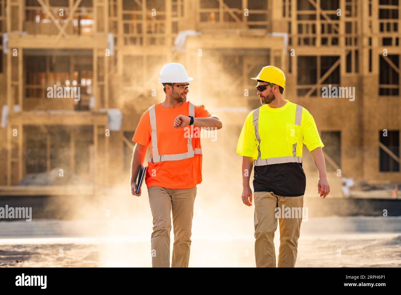 Two construction workers with hardhat helmet on construction site ...