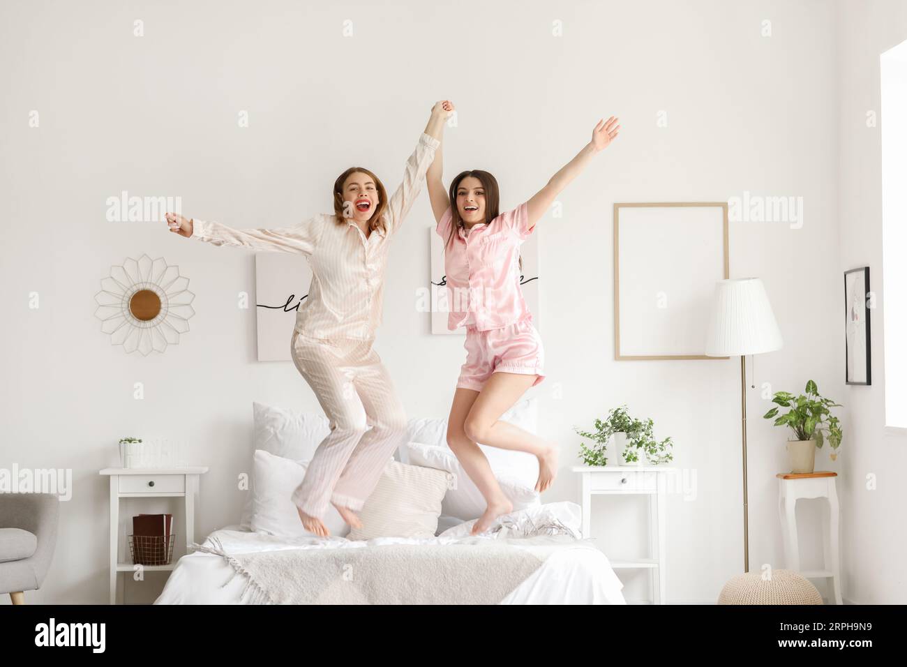Female friends jumping on bed at home Stock Photo - Alamy