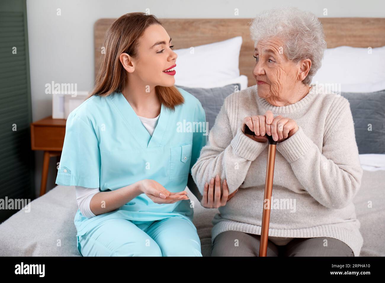 Female caregiver with senior woman in bedroom Stock Photo - Alamy